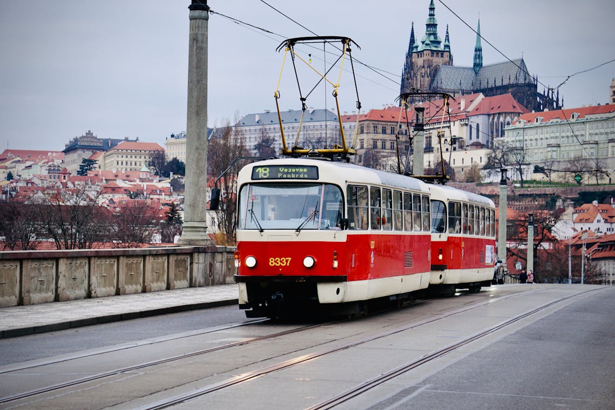 Vintage red and cream tram on a Prague city street with St Vitus Cathedral in the background