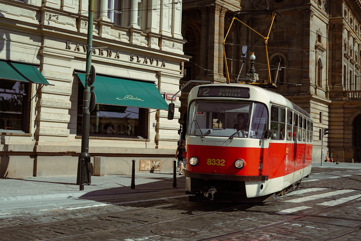 Red tram passing by historic buildings in Prague city centre on a sunny day