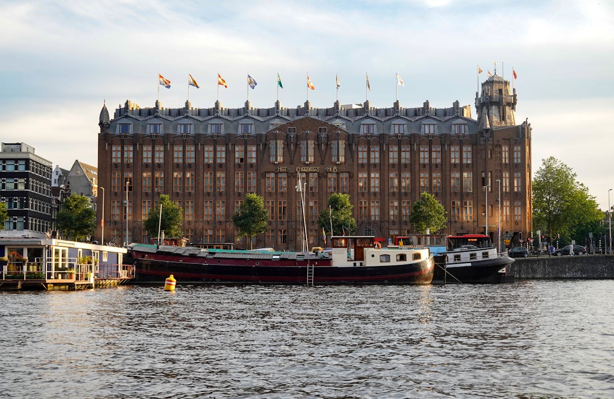 Grand Hotel Amrath Amsterdam building with boats on the canal in front under a blue sky