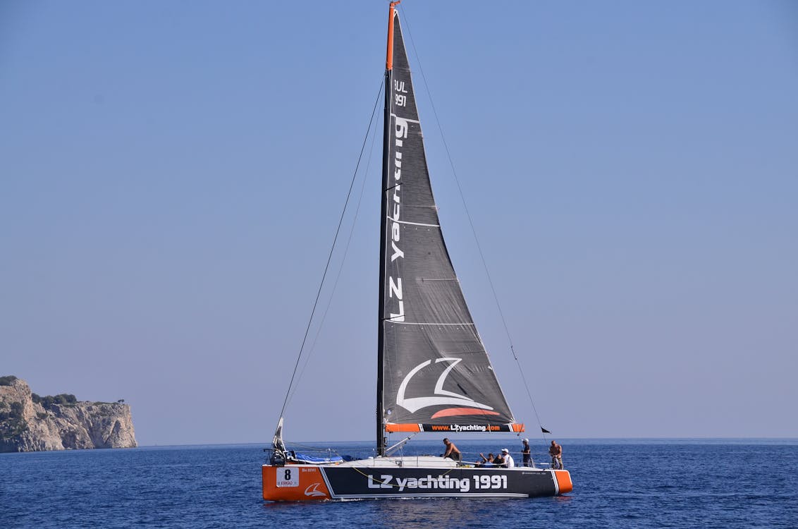 A sailboat gliding across the deep blue Mediterranean under a cloudless sky