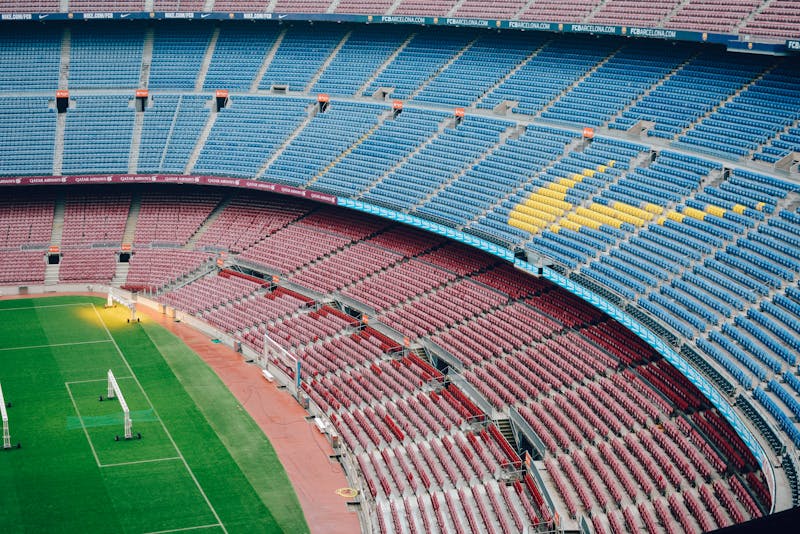 Aerial view of Camp Nou stadium showing colorful red and blue seats and green pitch