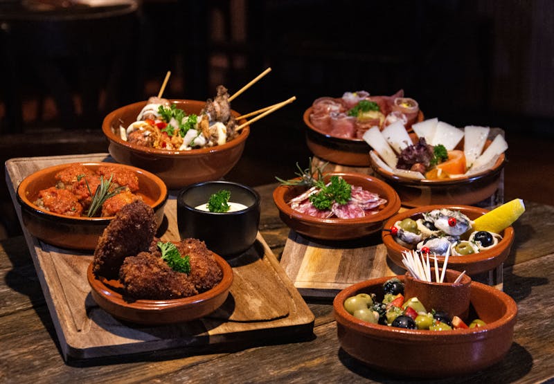 Multiple Spanish tapas dishes served on a rustic wooden table
