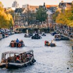 Tour boats cruising through Amsterdam canals with traditional Dutch buildings
