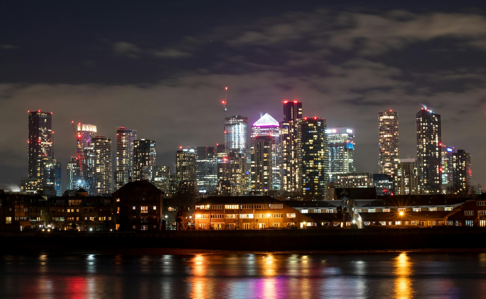 Canary Wharf financial district skyscrapers illuminated at night with reflections on the water