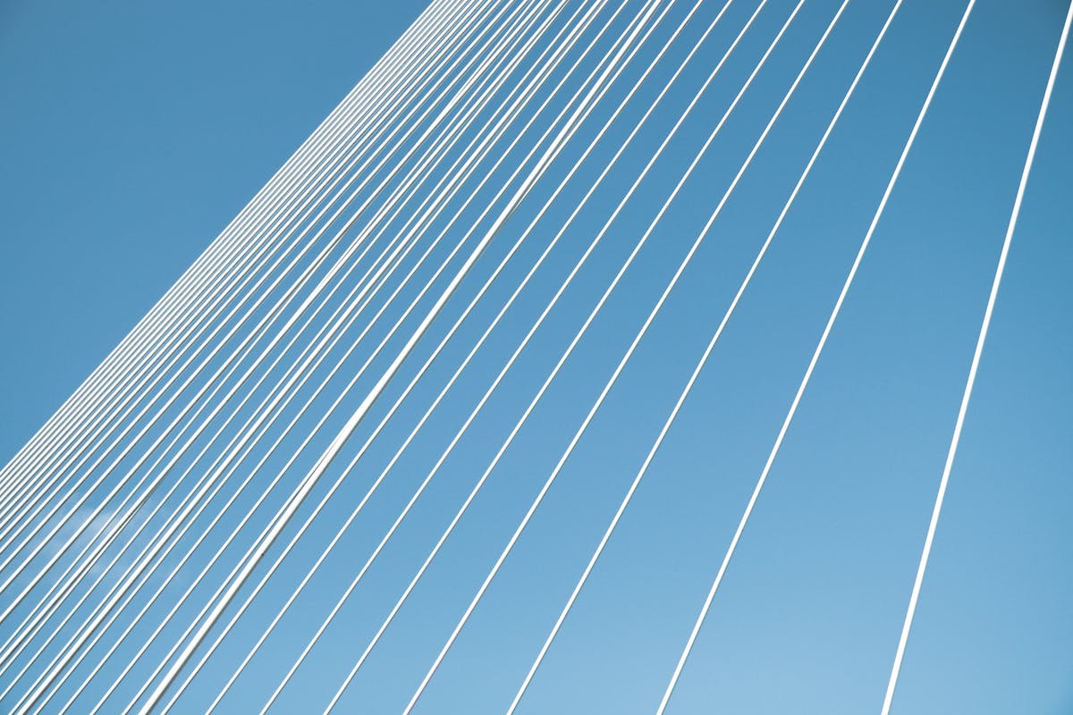 Steel cables of the Erasmus Bridge stretch against a clear blue sky in Rotterdam