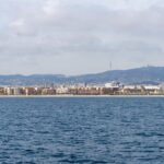 Panoramic view of Barcelona coastline with urban skyline and distant hills from the sea