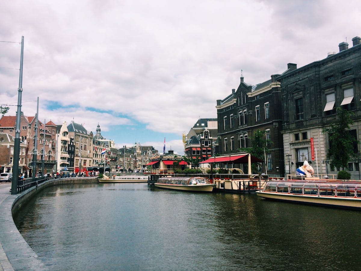 A canal in Amsterdam lined with historic buildings and tour boats, viewed from bridge level