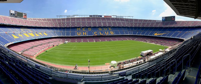 Panoramic view of Camp Nou stadium from pitch level showing the stands and green field