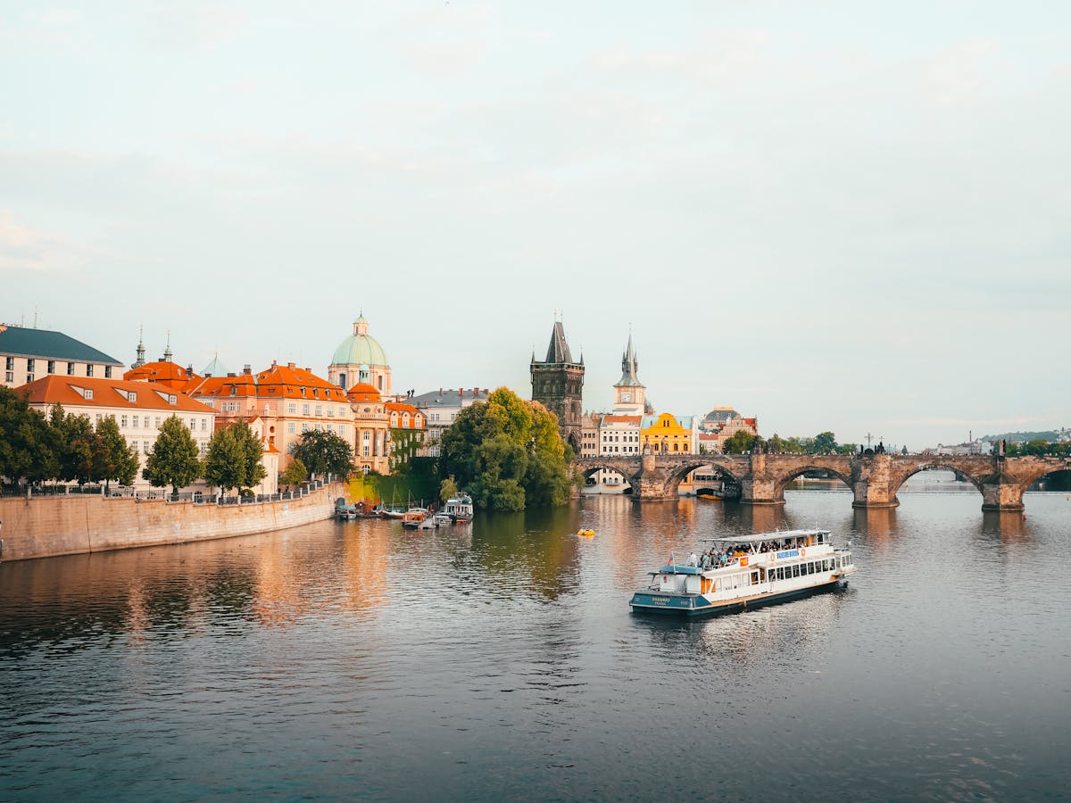 Aerial view of Charles Bridge and Prague skyline with a boat on the Vltava River