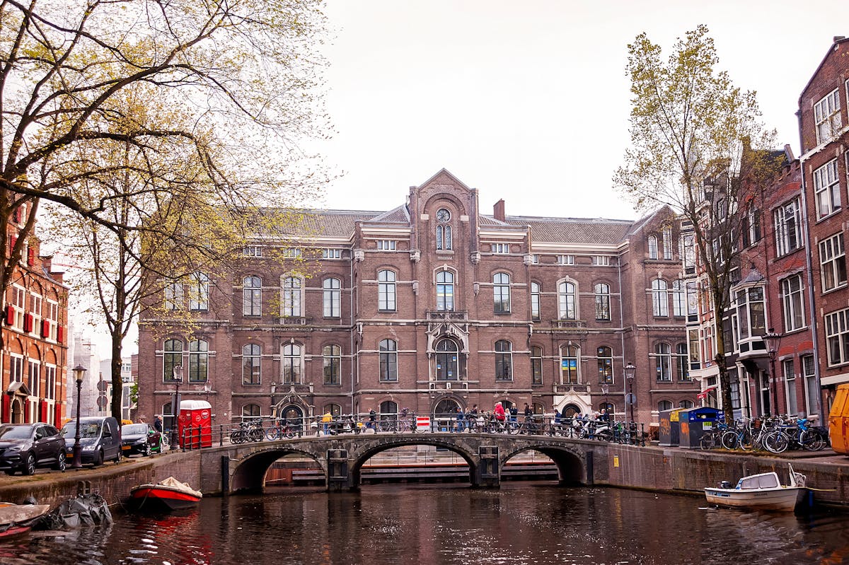 A picturesque Amsterdam canal with a bridge and building facade surrounded by spring greenery