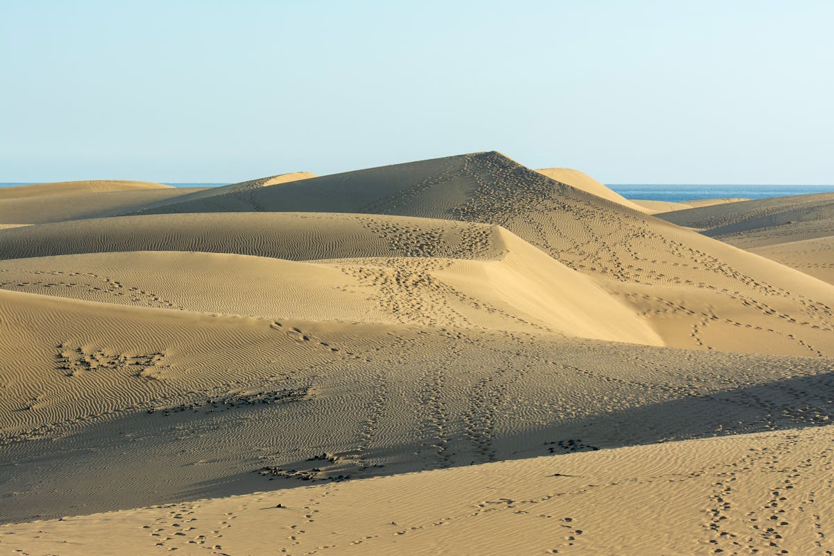 Vast sand dunes of Maspalomas with footprints in the sand under bright summer sunlight