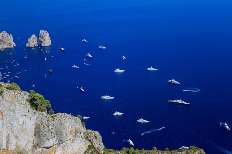 Aerial shot of yachts near the rocky coast of Capri Italy