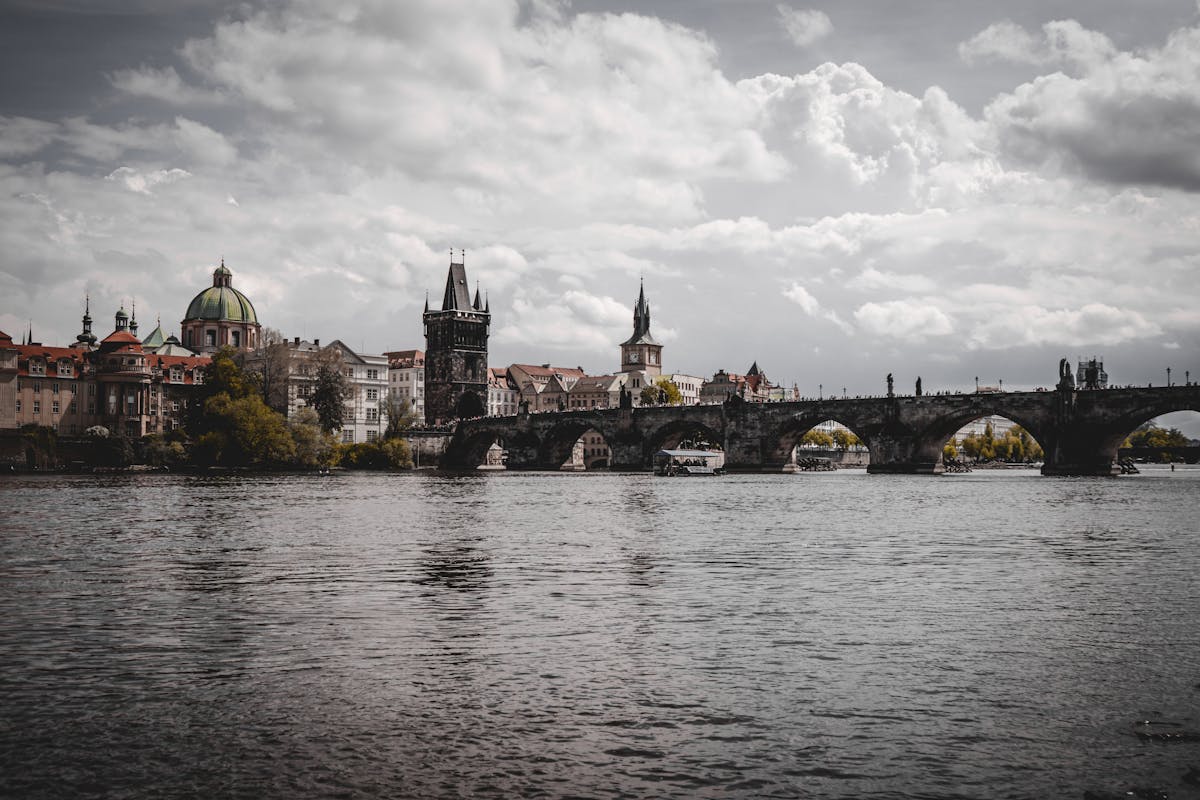 Iconic Charles Bridge spanning the Vltava River with Prague skyline and cloudy sky