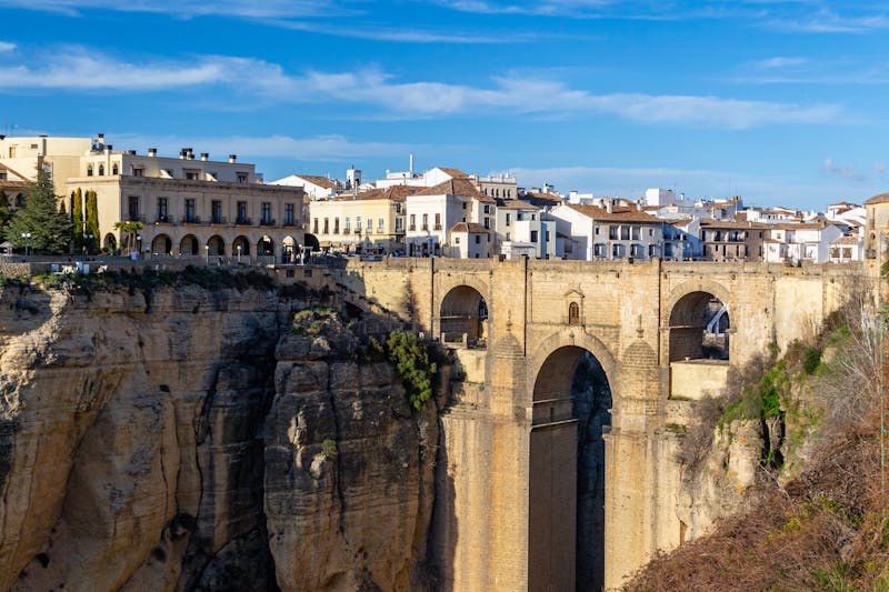 The Puente Nuevo bridge spanning the deep El Tajo gorge in Ronda, Spain, with white buildings perched on the cliff edge