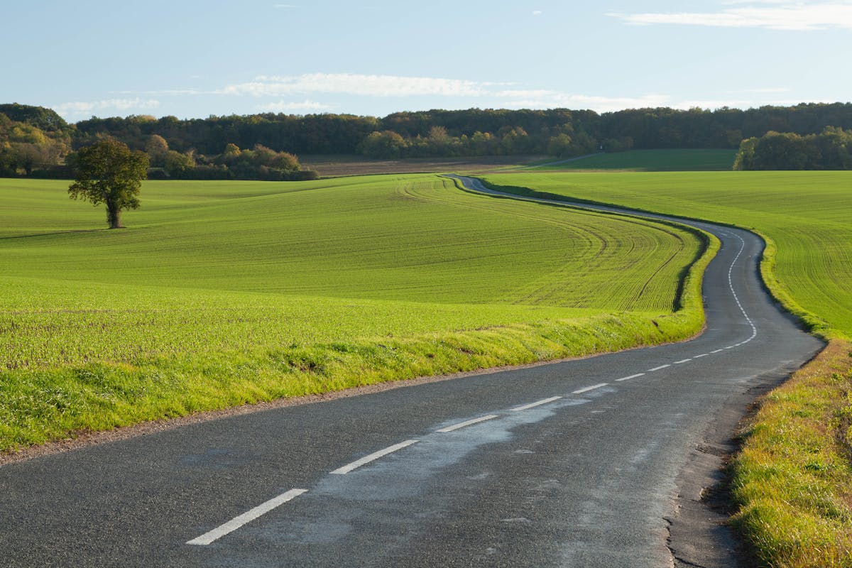 Peaceful countryside road winding through lush green fields in northern France