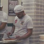 Pizza chef spreading sauce on pizza dough in a Naples restaurant kitchen