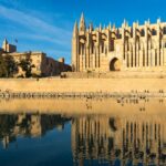 Palma Cathedral reflecting in the water of Parc de la Mar under a clear blue sky