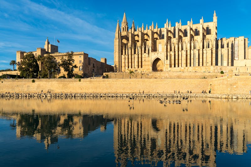 Palma Cathedral reflecting in the water of Parc de la Mar under a clear blue sky