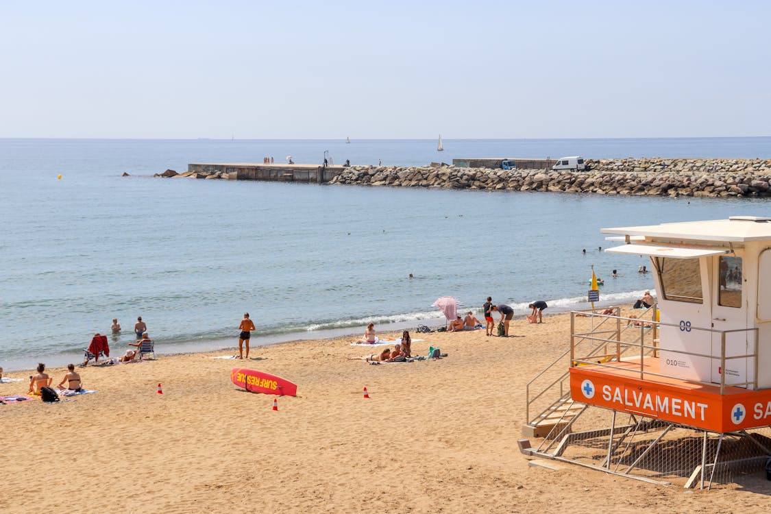 Lively beach scene at Barceloneta in Barcelona with lifeguard tower and sunbathers