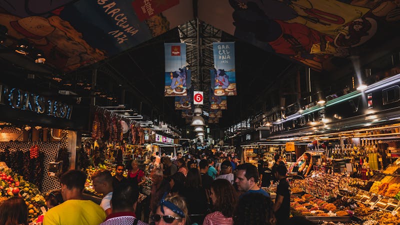 Busy market scene in Barcelona with visitors browsing food stalls