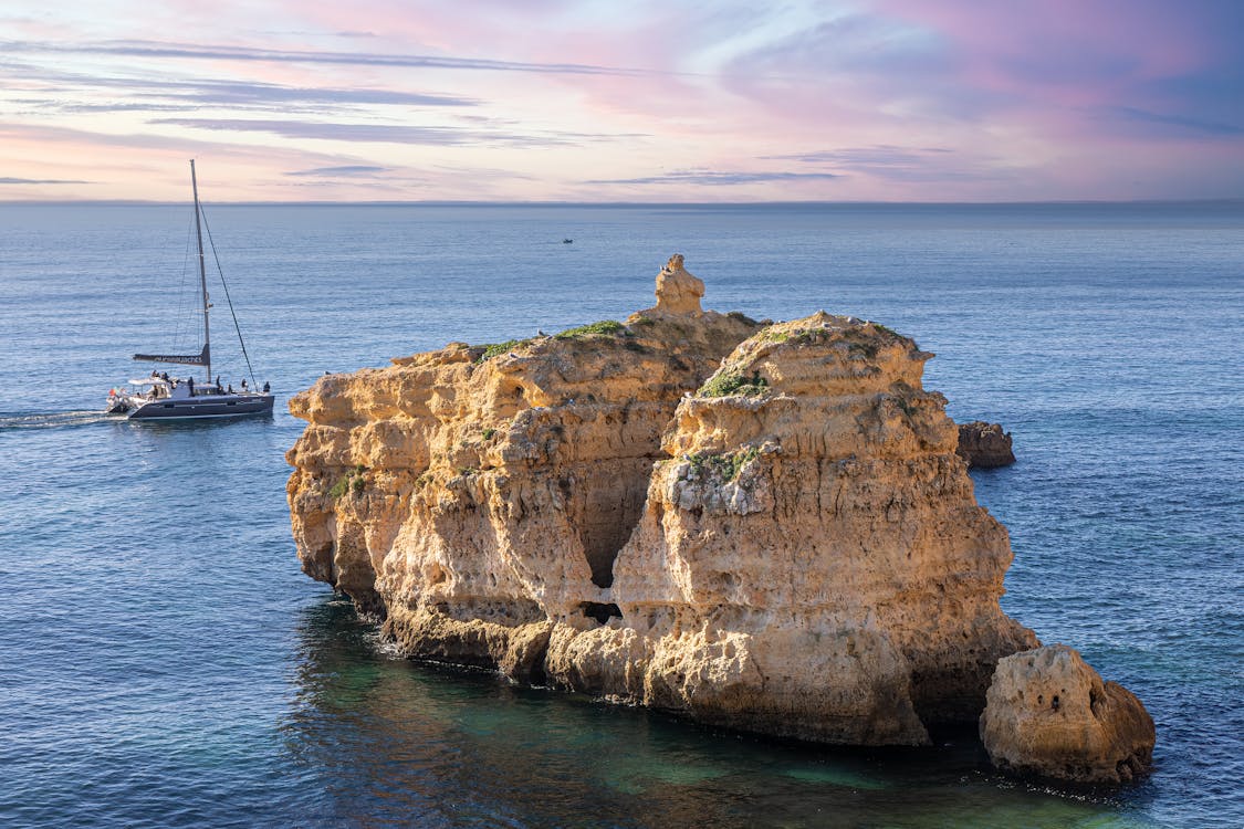 Sailboat cruising near rock formations in the Azores during sunset