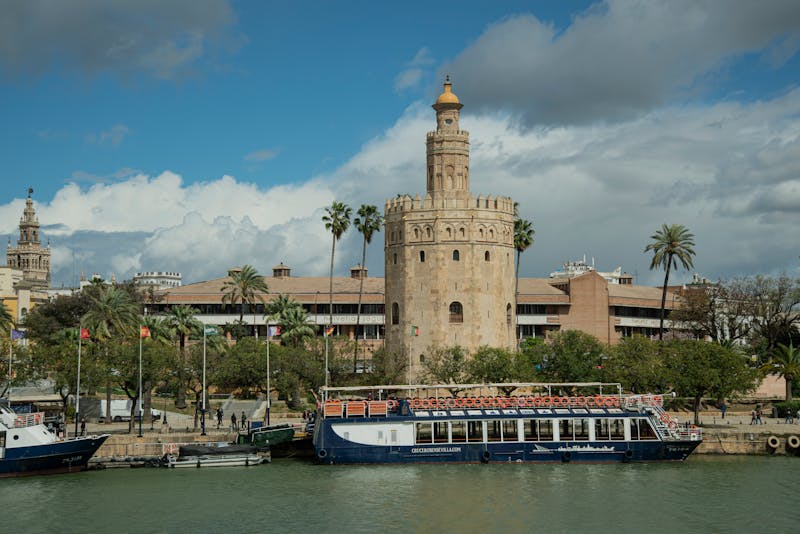 Historic Torre del Oro tower overlooking a boat on the Guadalquivir River in Seville Spain