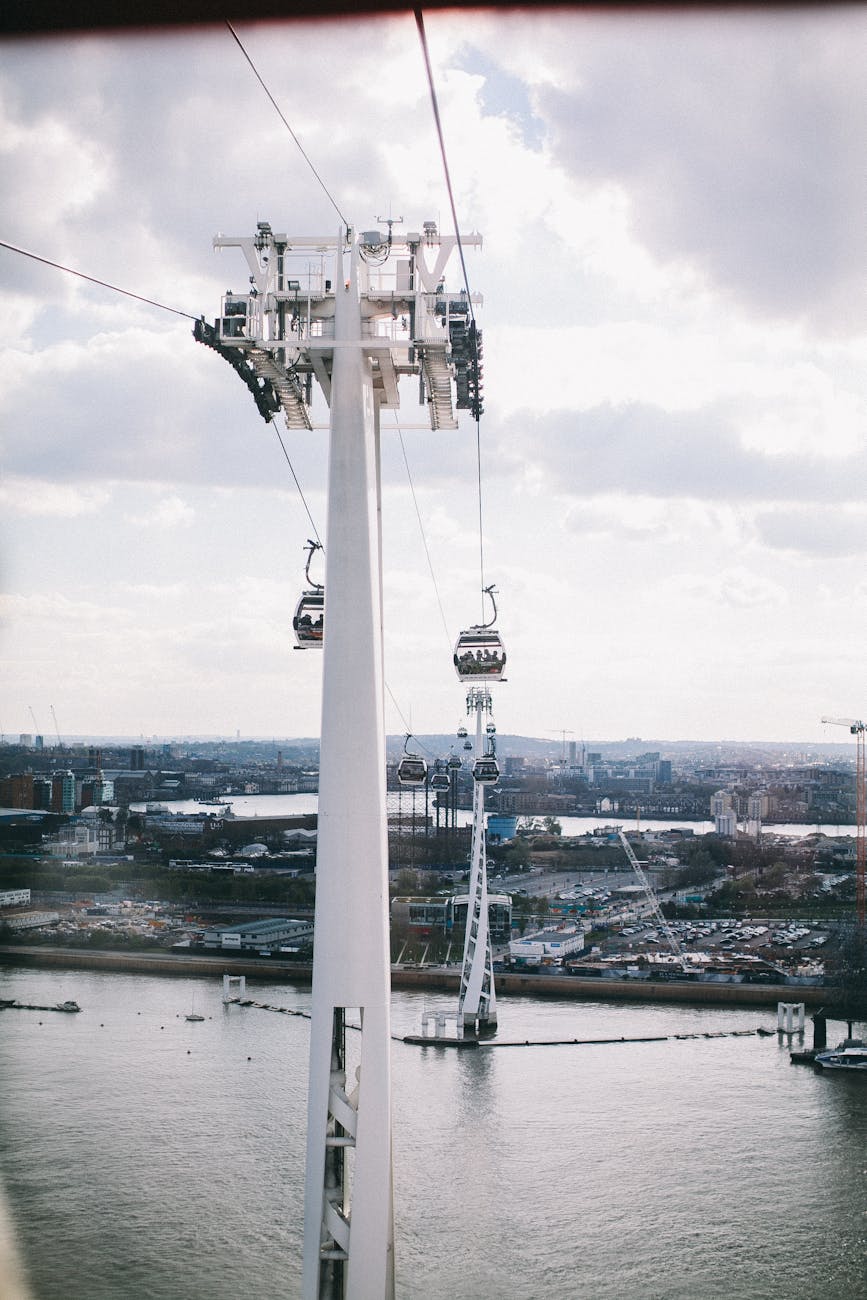 Cable car gondolas traveling over the River Thames with modern high-rise buildings and the London skyline visible in the distance