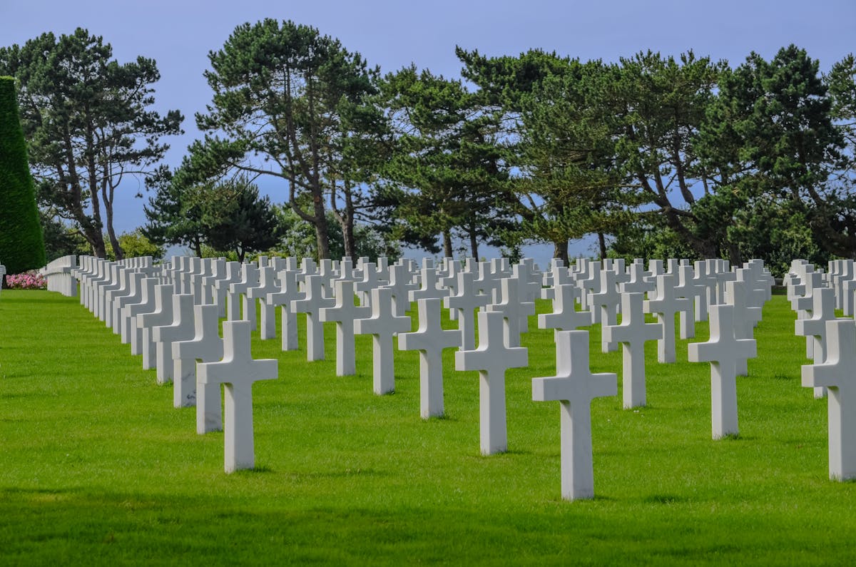 Visitors paying respects at the Normandy American Cemetery with white crosses in rows