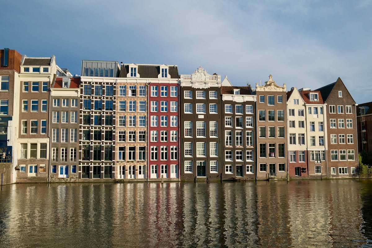 An elegant row of Amsterdam canal houses with clear reflections in the calm water