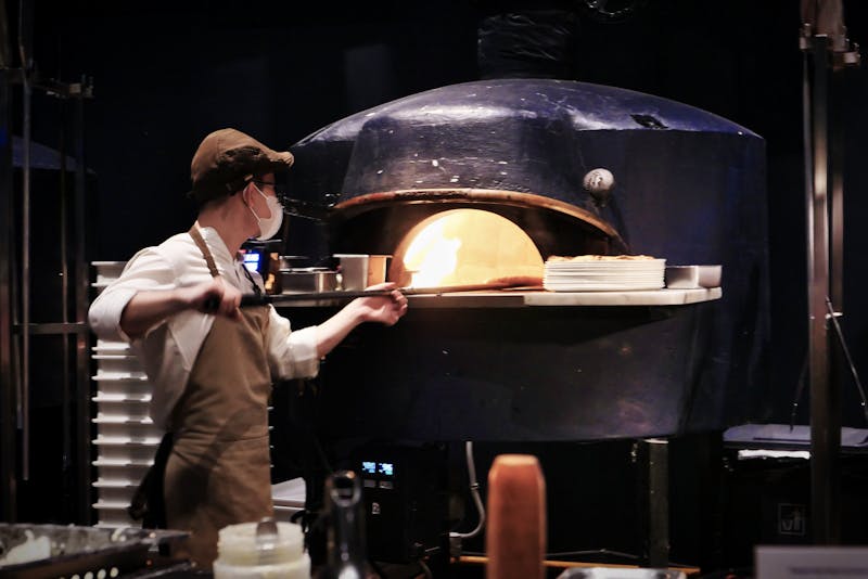 Chef skillfully placing a pizza into a traditional wood-fired oven