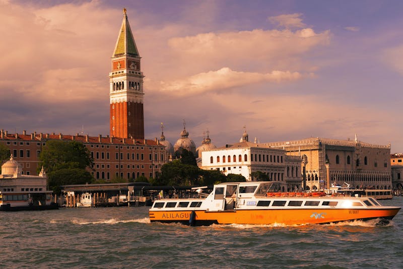 Venice canal with vaporetto and the Campanile di San Marco bell tower at sunset