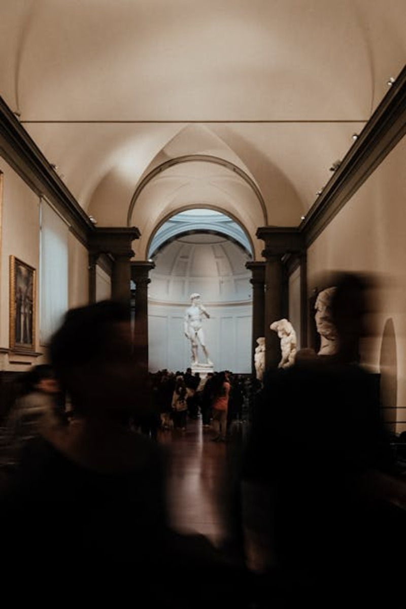 Visitors admiring Renaissance sculptures displayed in an Italian art gallery hall
