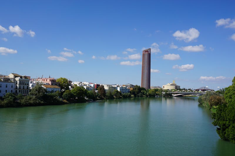 Torre Sevilla skyscraper overlooking the Guadalquivir River under a clear blue sky in Seville