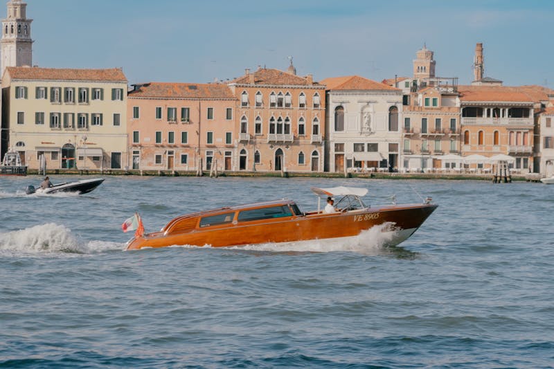 A traditional Venetian water taxi cruising along the Grand Canal with historic buildings