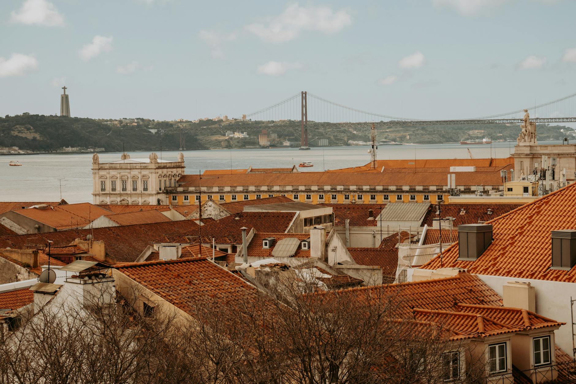 Panoramic view of Lisbon terracotta rooftops with the 25th April Bridge spanning the Tagus River