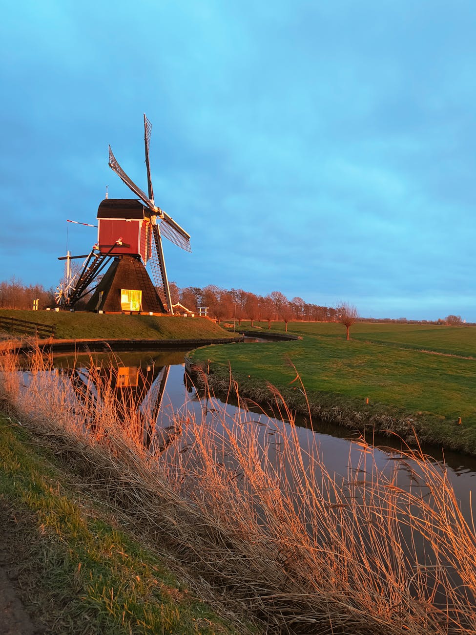 Dutch windmill reflected in a canal at sunset in the Netherlands countryside