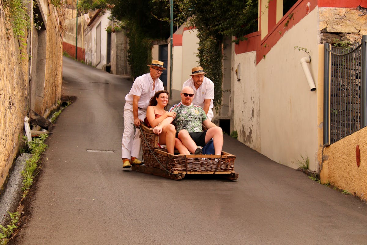 Tourists enjoying a traditional wicker toboggan ride in Funchal Madeira