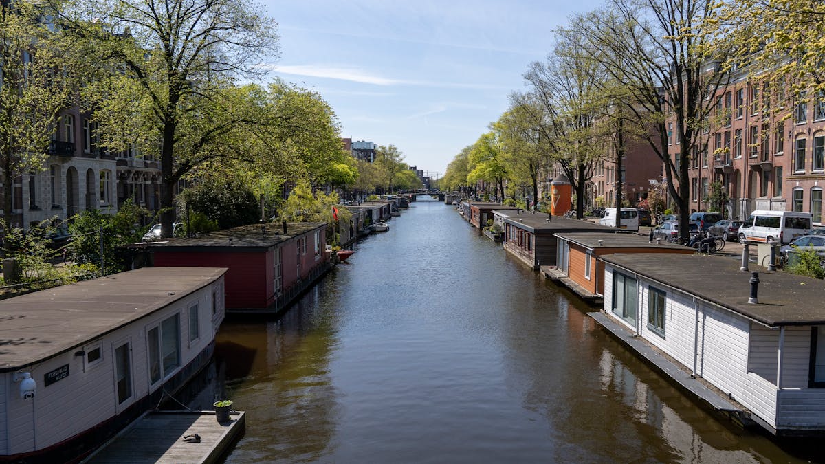 Amsterdam canal lined with houseboats and spring blossoms