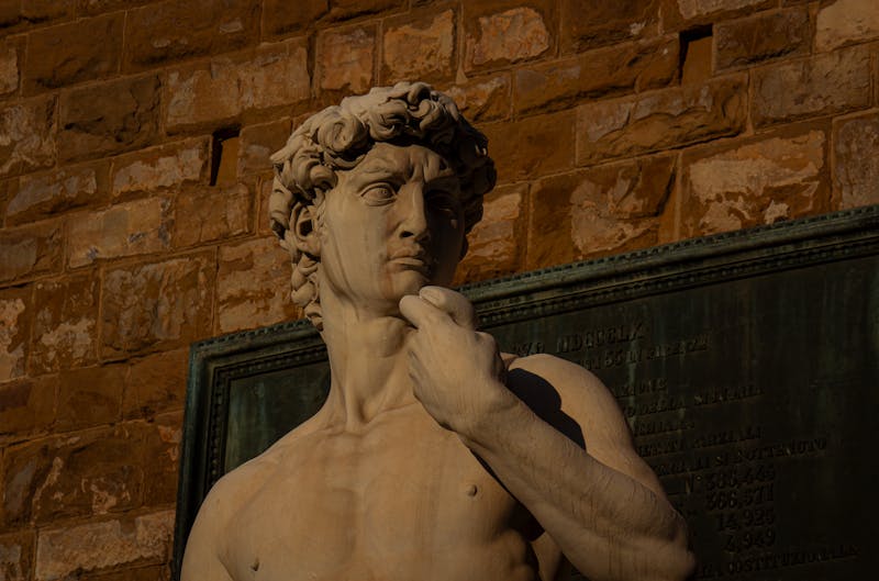 Close-up of the face and upper body of Michelangelos David statue with dramatic lighting