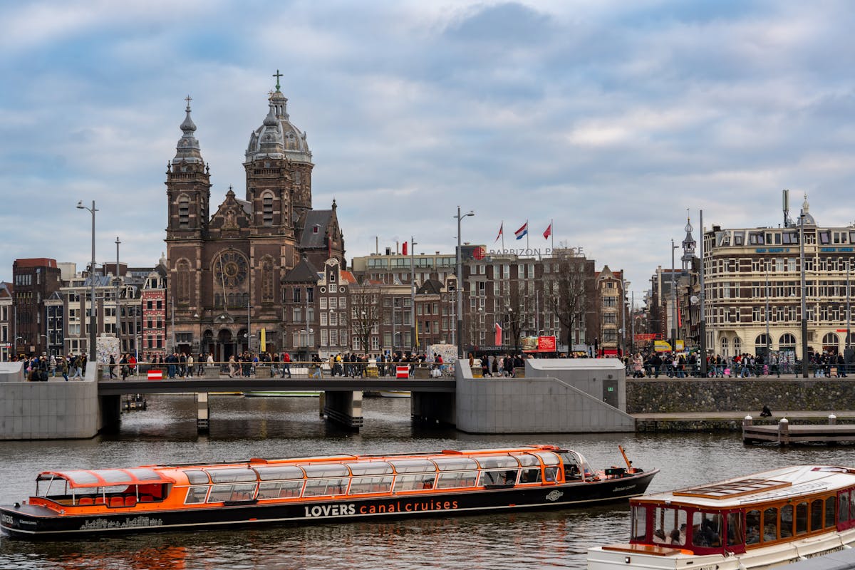 Scenic view of the Basilica of Saint Nicholas alongside Amsterdam canal with boats