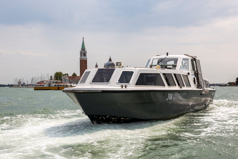 Water taxi cruising past San Giorgio Maggiore island in Venice under cloudy sky