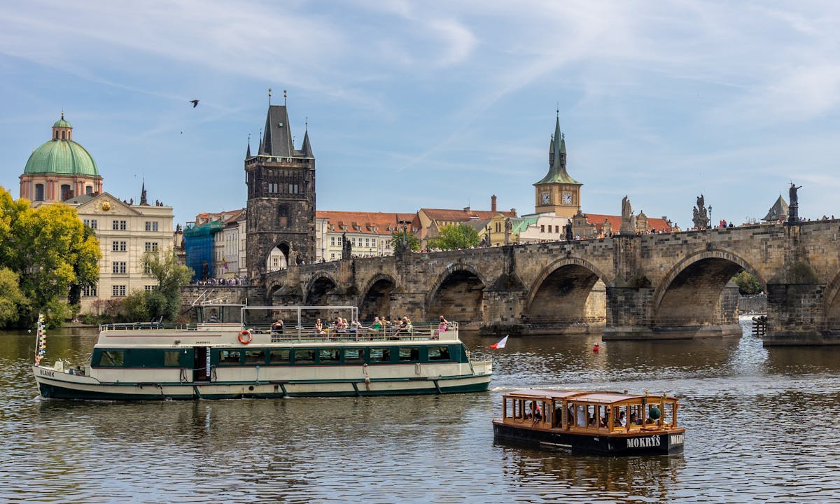 Sightseeing cruise boat on the Vltava River with Charles Bridge and Prague buildings in the background