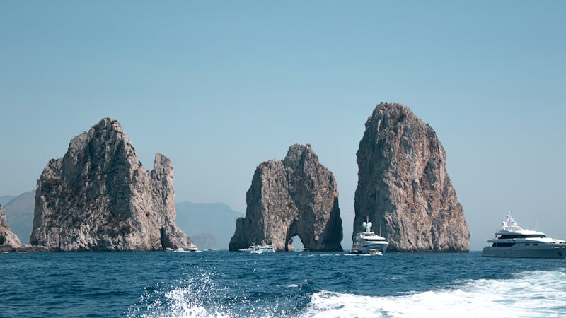 Faraglioni rocks from the sea with yachts