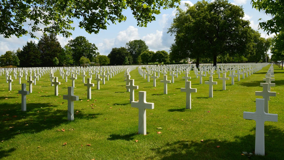 Peaceful cemetery landscape with rows of white crosses in Normandy under blue sky