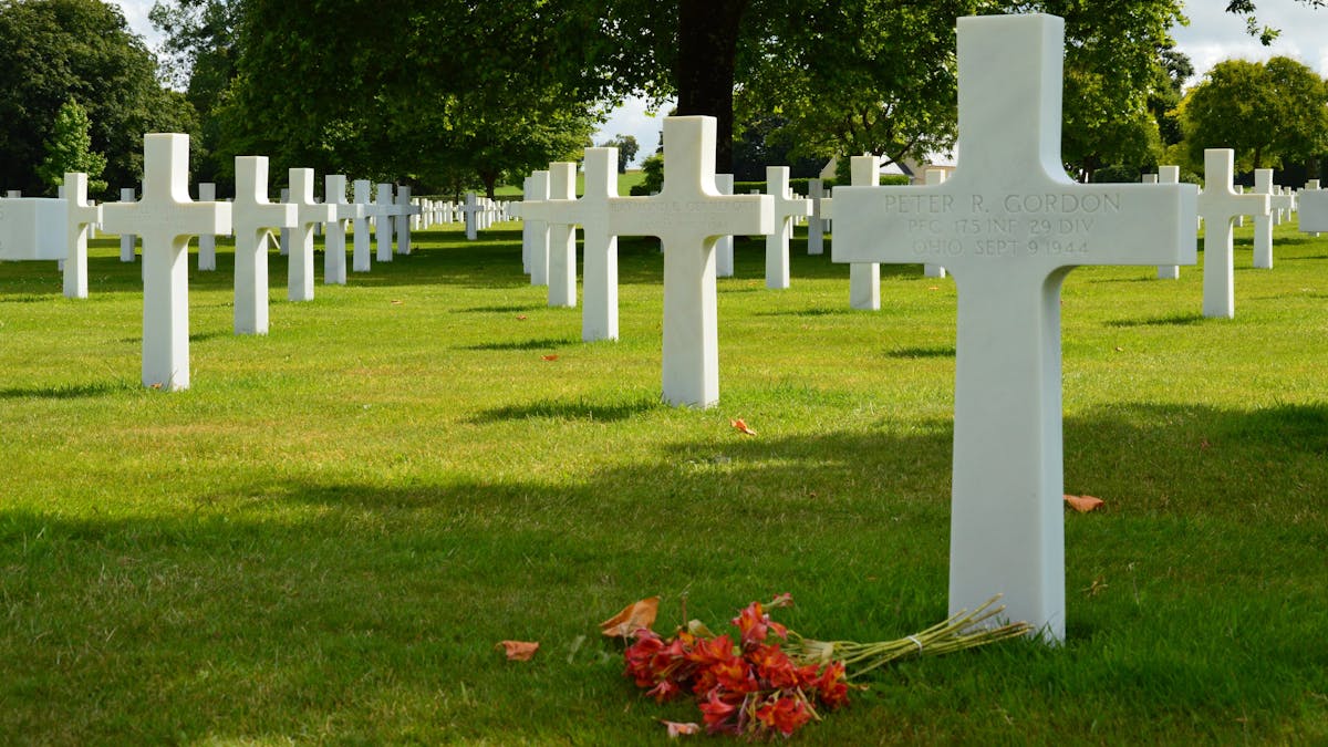 Rows of white crosses in a World War II cemetery under clear skies