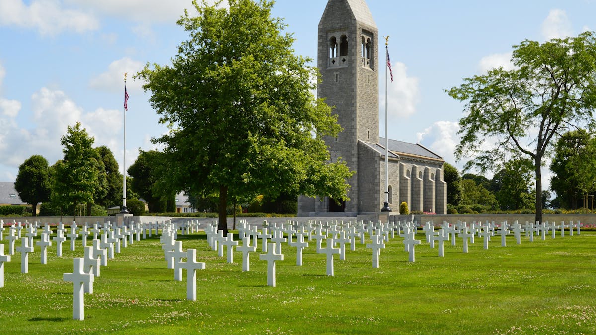 Rows of white marble crosses stretching across the green lawn of the Normandy American Cemetery