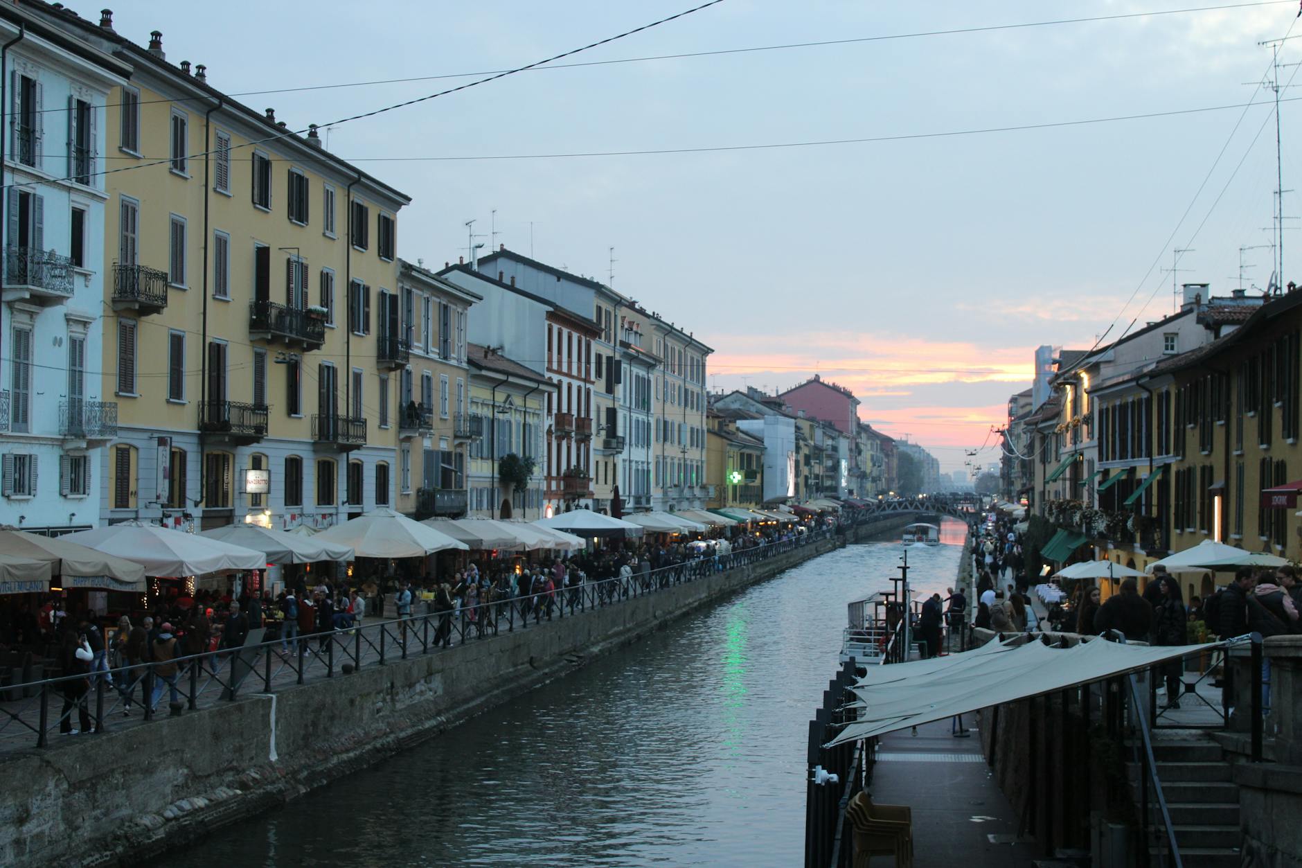 Evening view of Naviglio Grande canal with restaurants and lights reflecting on the water