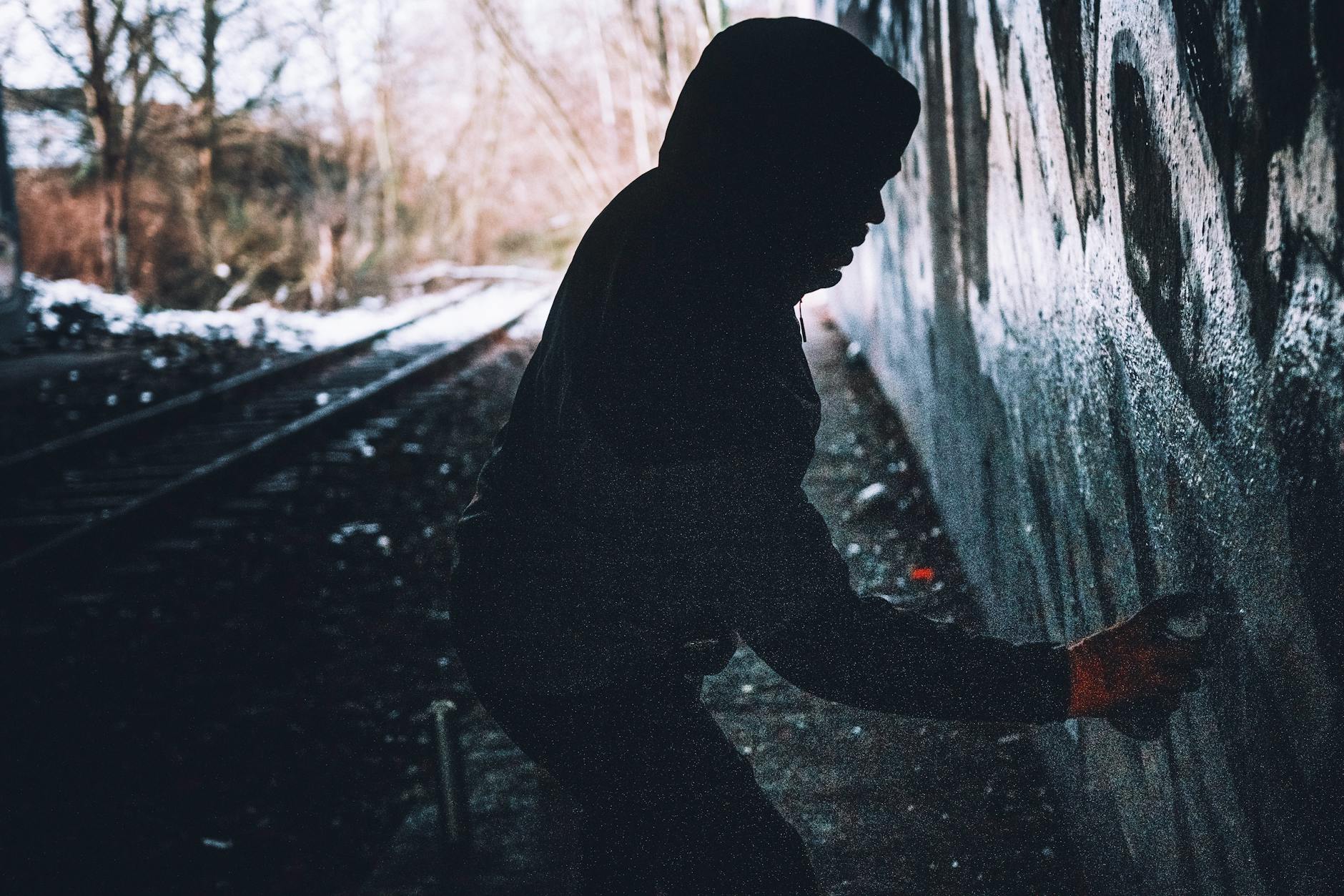 Street artist spray painting graffiti on Berlin wall