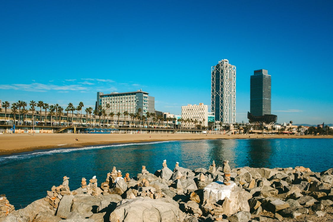 Sunny view of Barcelona beachline with skyscrapers and rock formations along the coast