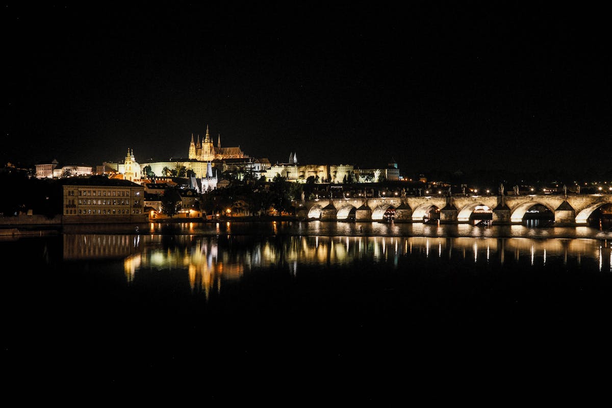 Night panorama of Prague showing Charles Bridge and Prague Castle with reflections on the Vltava River